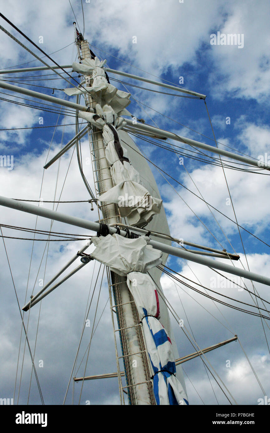 View to the top of a sailing ship showing the mast and folded sails ...