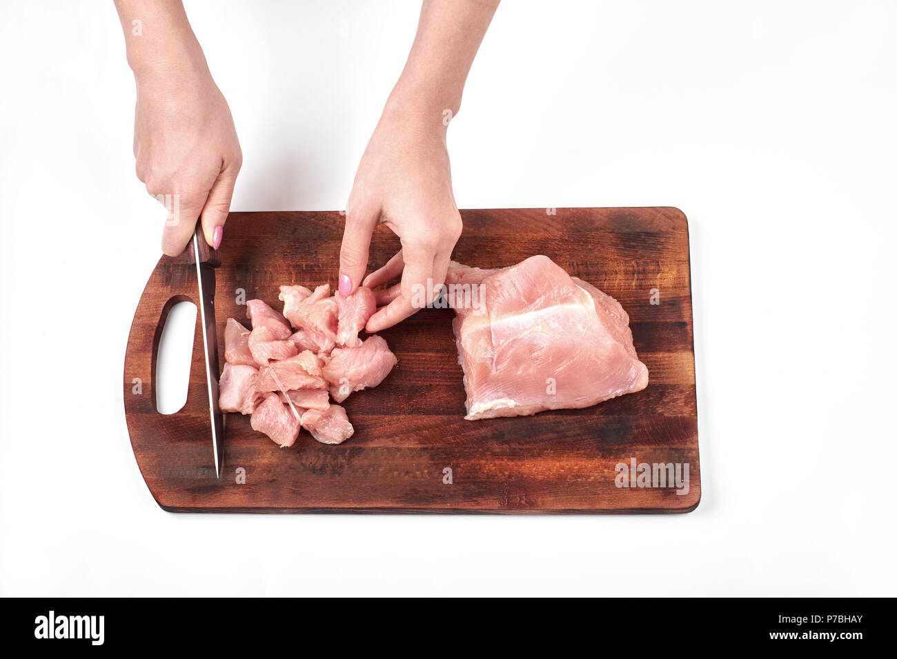 Cutting raw turkey meat with a kitchen knife on a cutting board ...