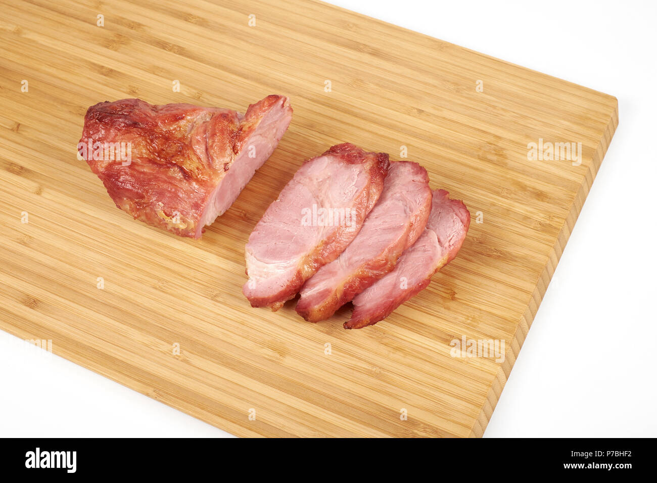 Cooked sliced pork barbecue steak on wooden cutting board on the white ...