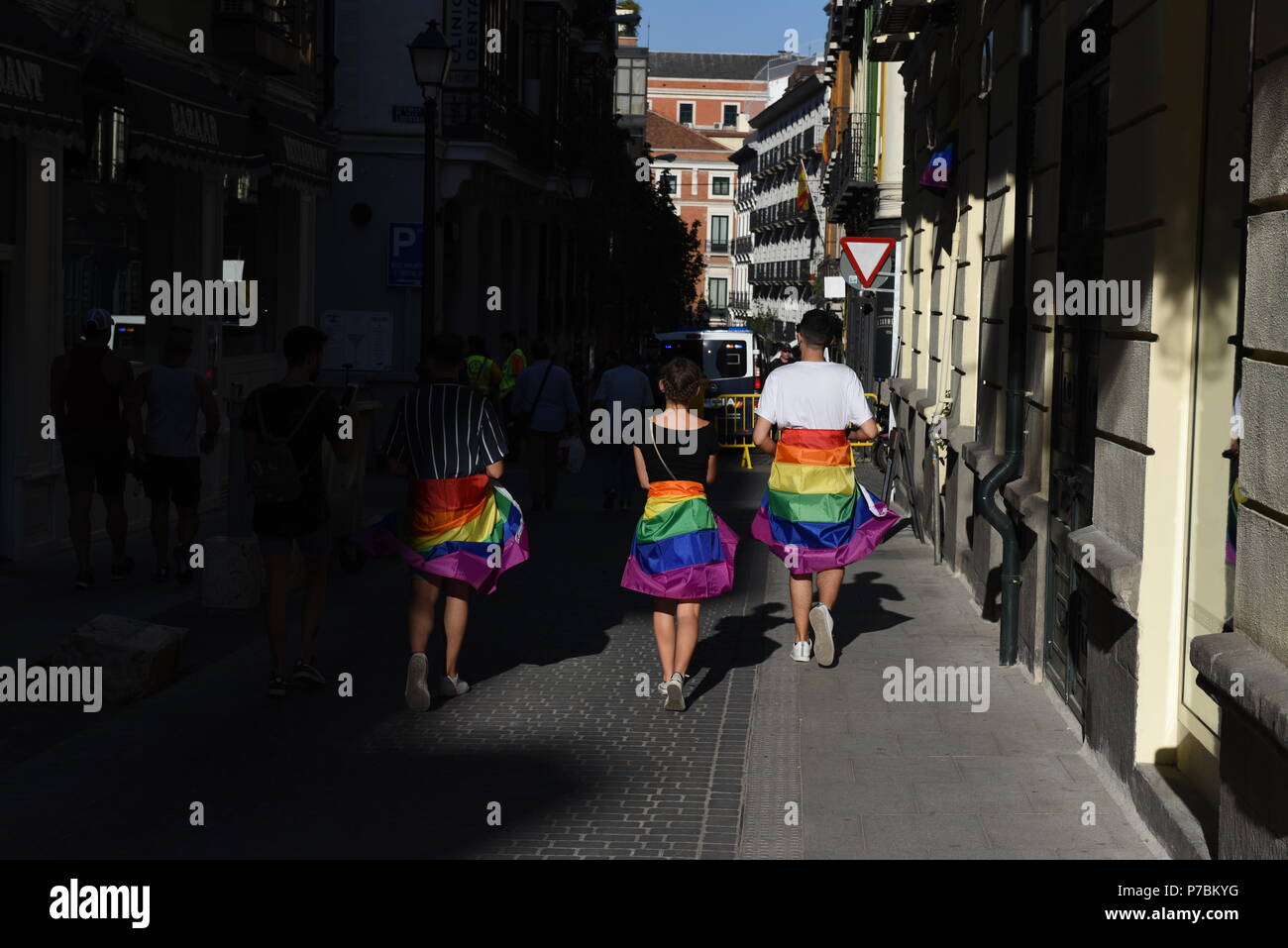 People walk with Gay Pride rainbow flags around their waists on a ...