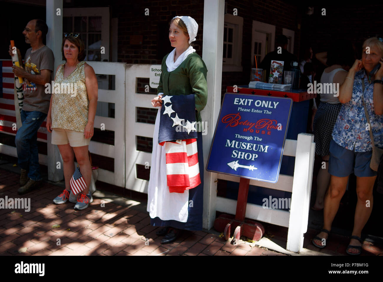 A woman dressed in a colonial outfit watches a naturalization ceremony ...