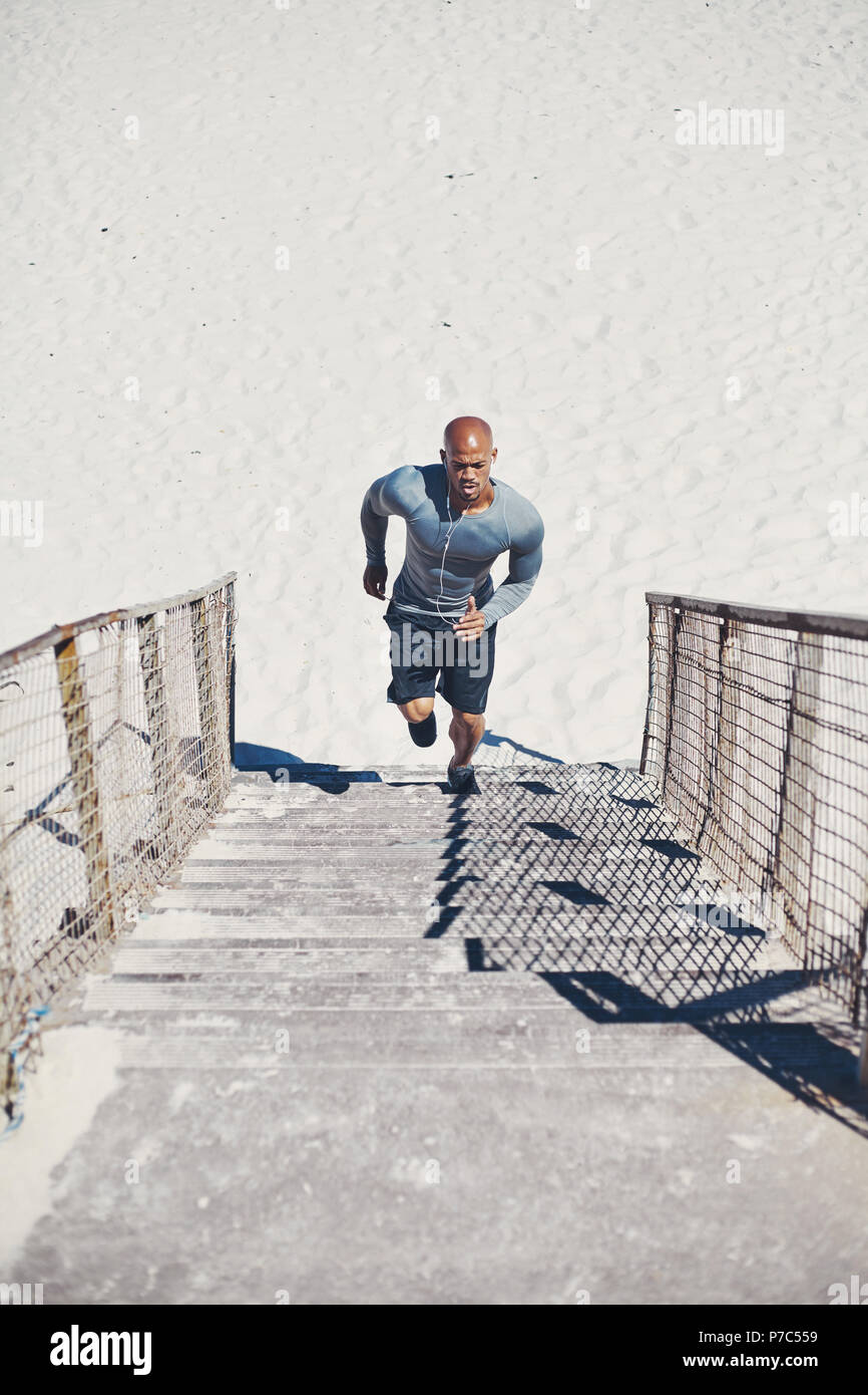 Fitness man running upstairs on beach Stock Photo - Alamy