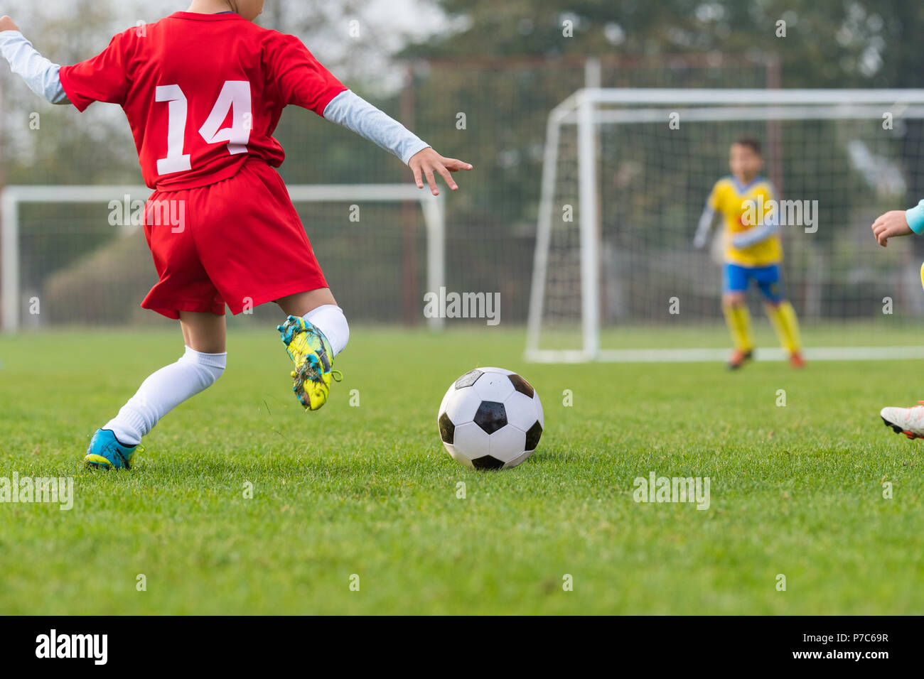 Boy kicking soccer ball on sports field Stock Photo - Alamy