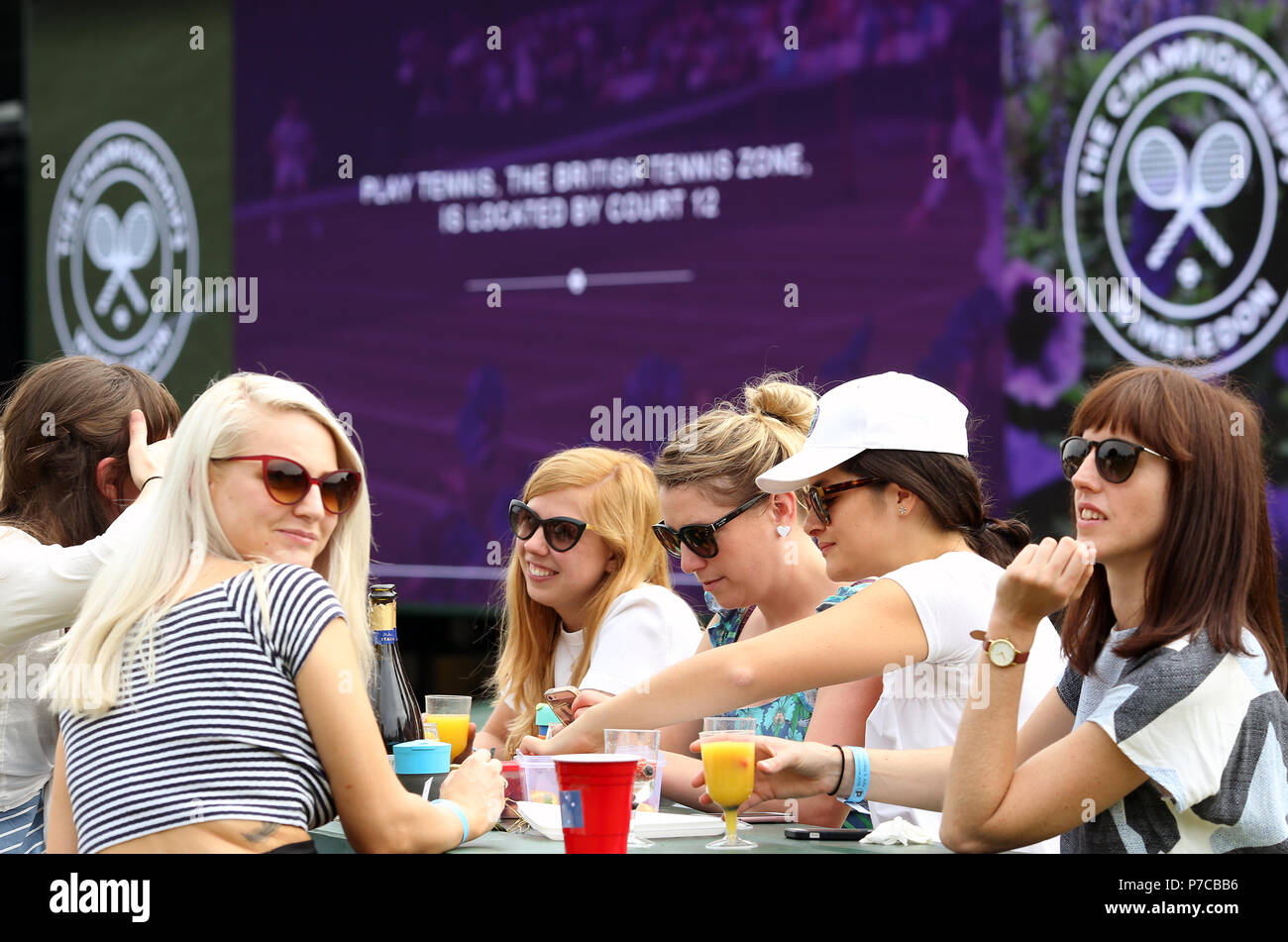 Spectators at a picnic bench at the start of day four of the Wimbledon ...