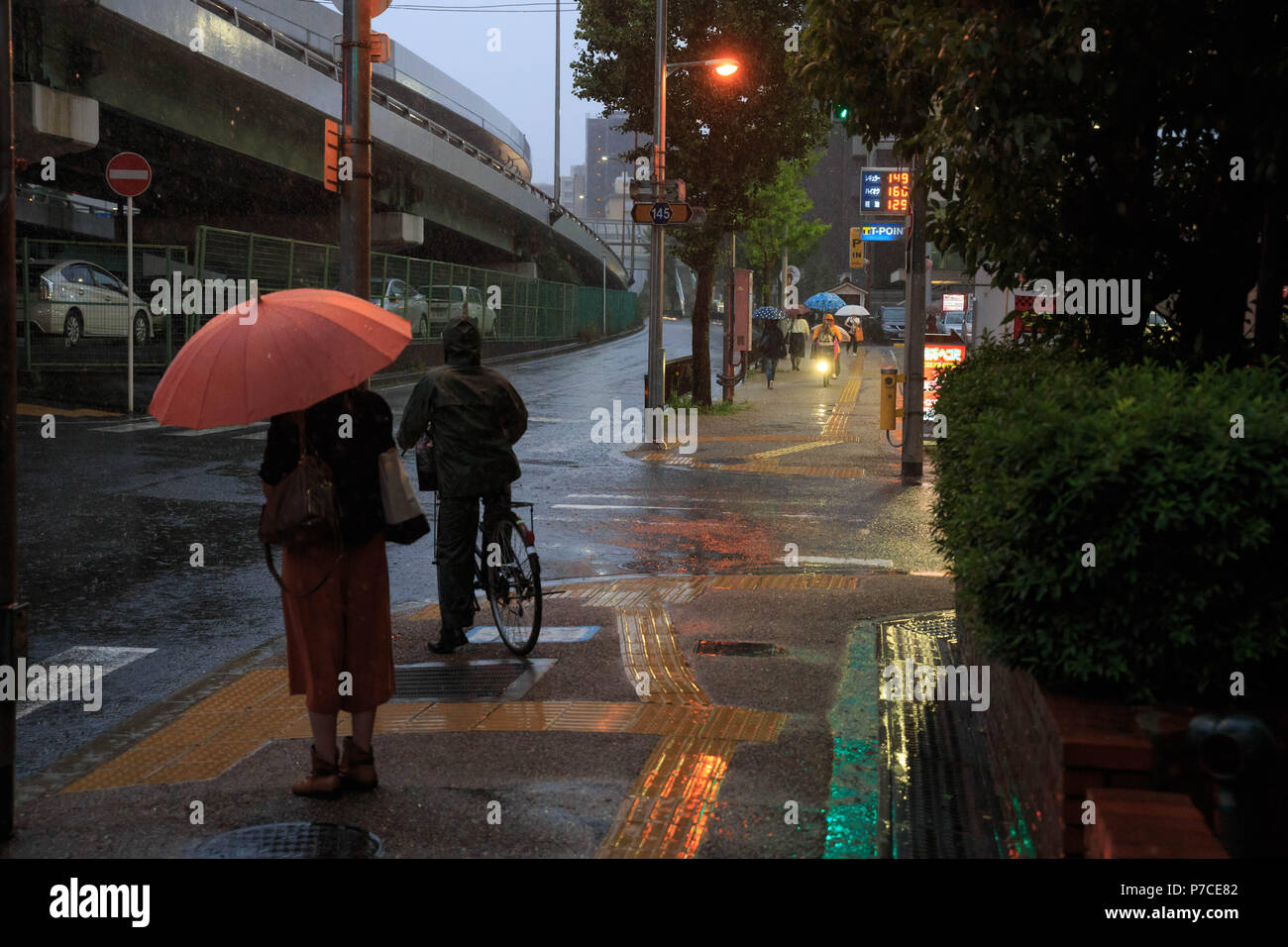 Osaka, Japan - July 5, 2018: Woman with umbrella and man riding bicycle ...