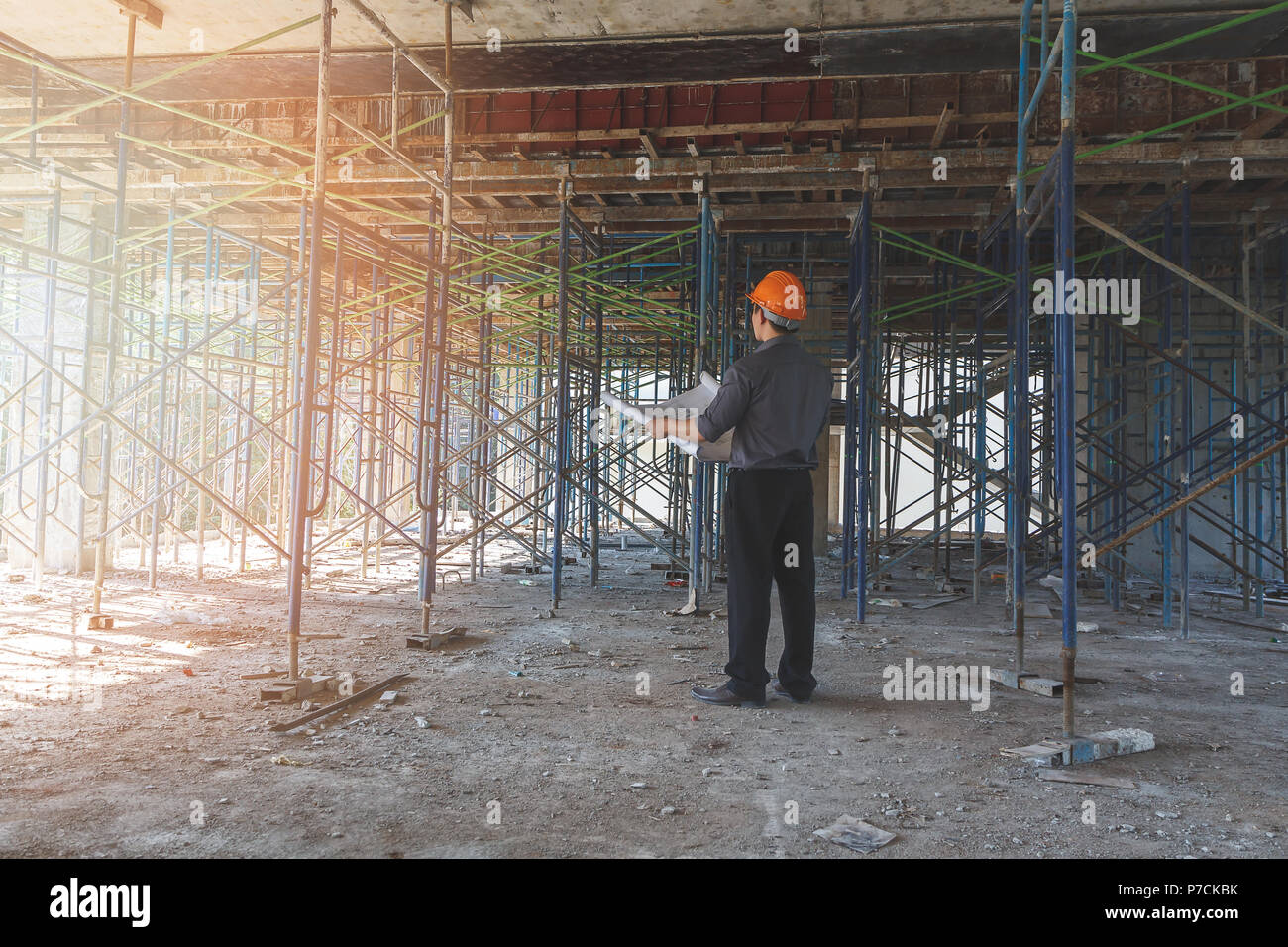 Engineer with blueprint in building construction site Stock Photo - Alamy