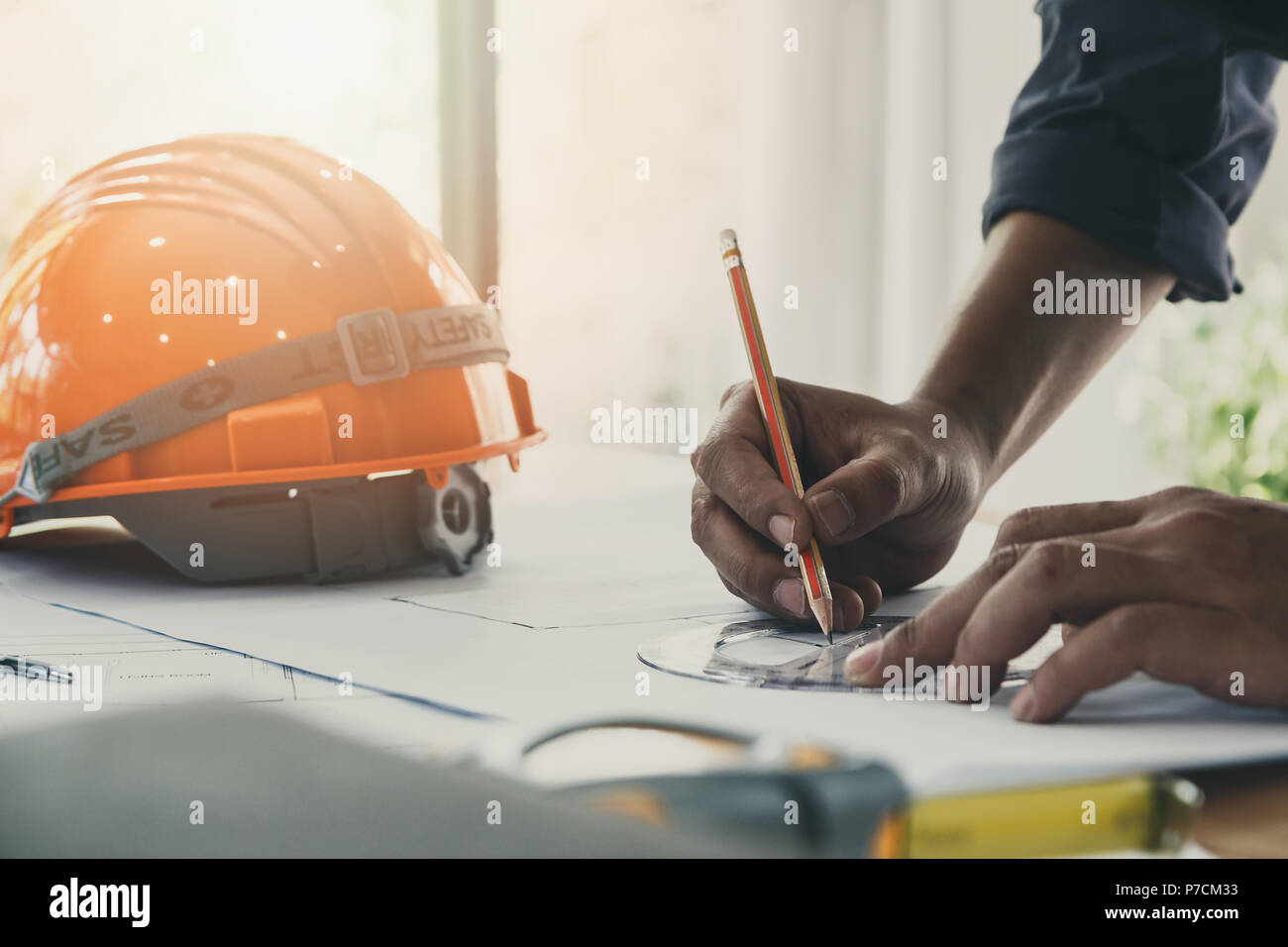 Architect or engineer using pencil and protractor working on blueprint ...