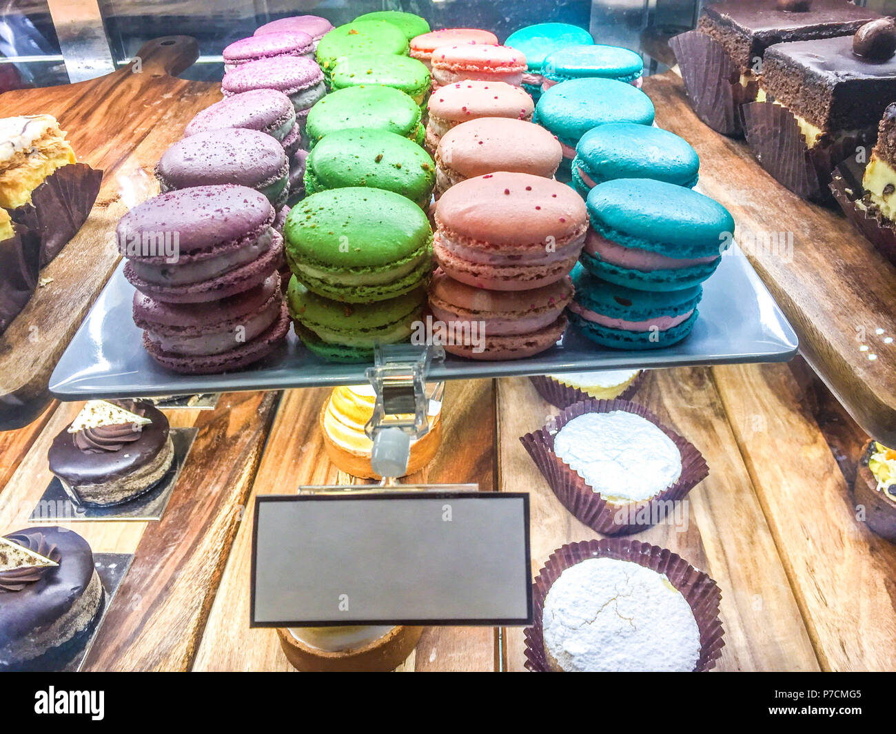 Colorful rows of macaroons in cafe storefront display window with copy ...
