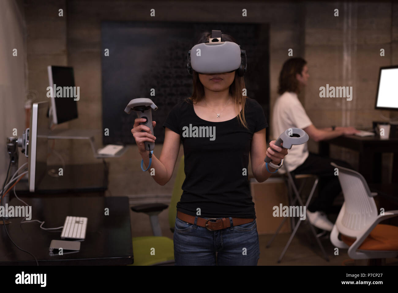 Female executive using virtual reality headset with controller Stock ...