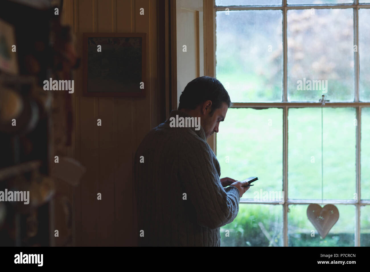 Man using mobile phone near window Stock Photo - Alamy