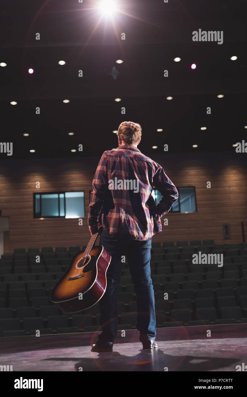 Man standing with guitar on stage Stock Photo - Alamy