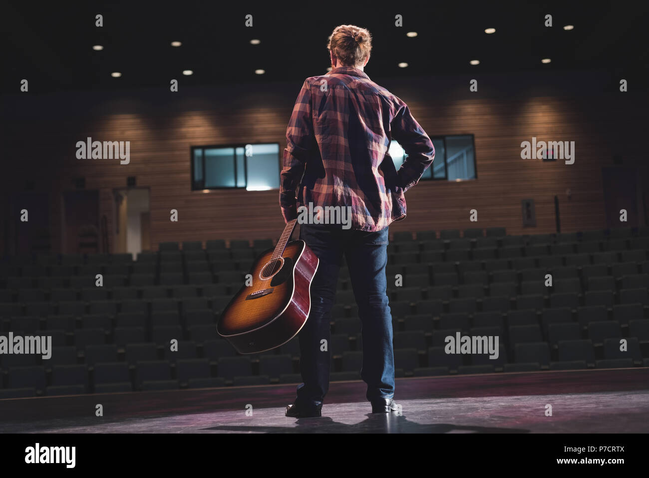 Man standing with guitar on stage Stock Photo - Alamy