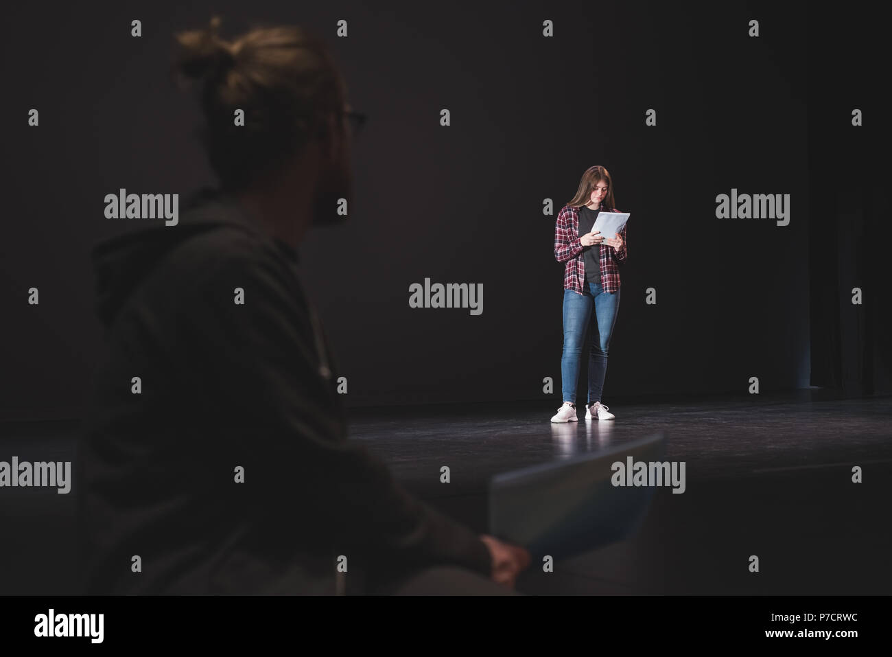 Female actress reading script while male actor looking at her on stage ...