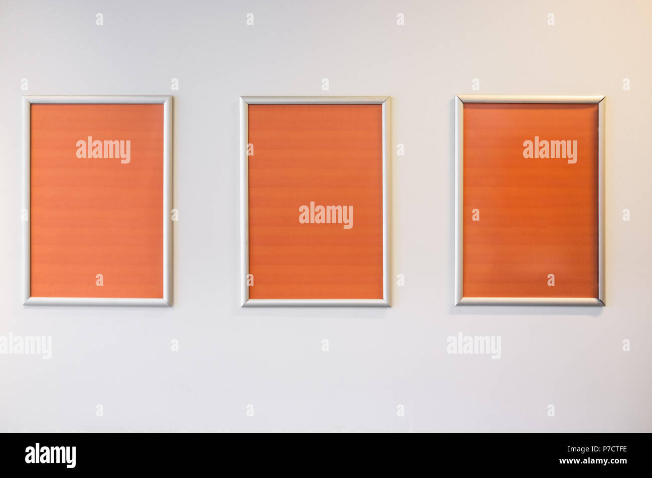 Three picture frames with orange copy space hanging on white wall Stock ...