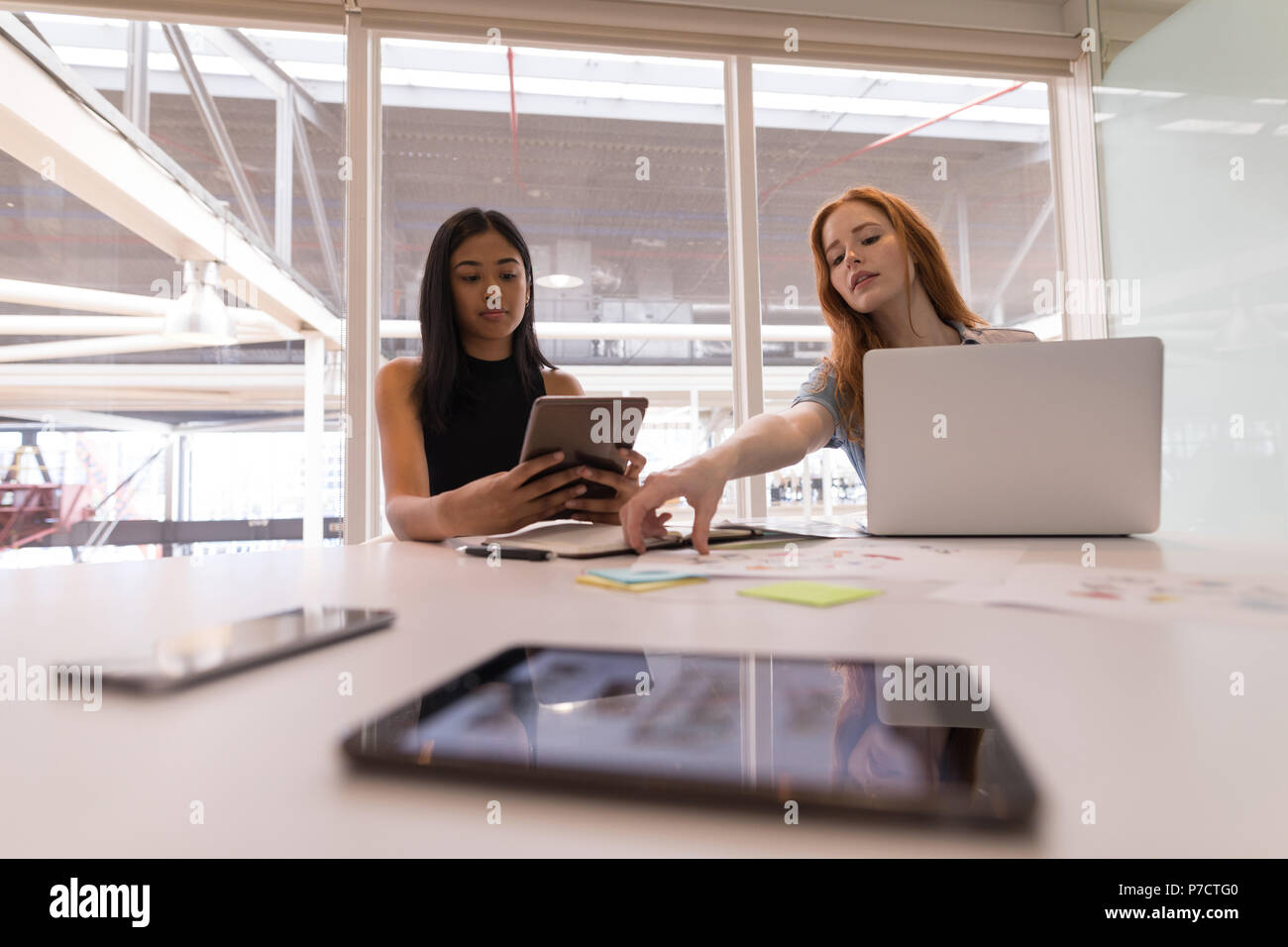 Female executives using digital tablet and laptop at desk Stock Photo ...