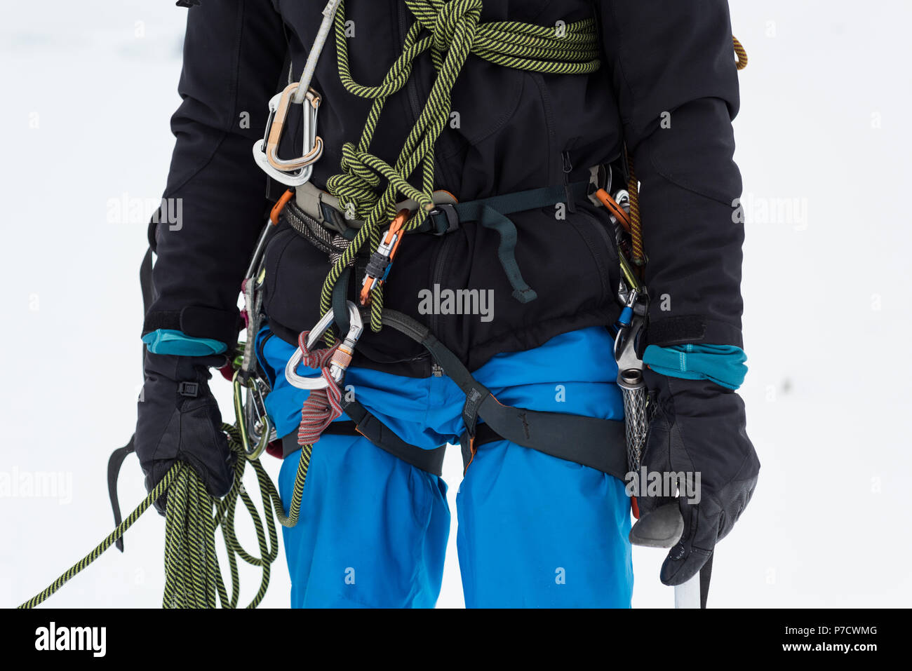 Male mountaineer standing with rope and harness on a snowy region Stock ...
