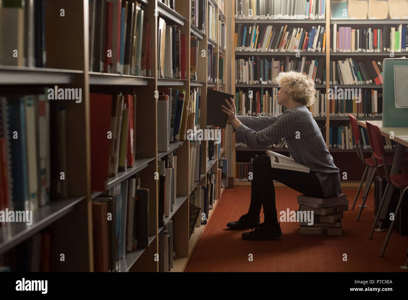 Woman removing book from shelf hi-res stock photography and images - Alamy