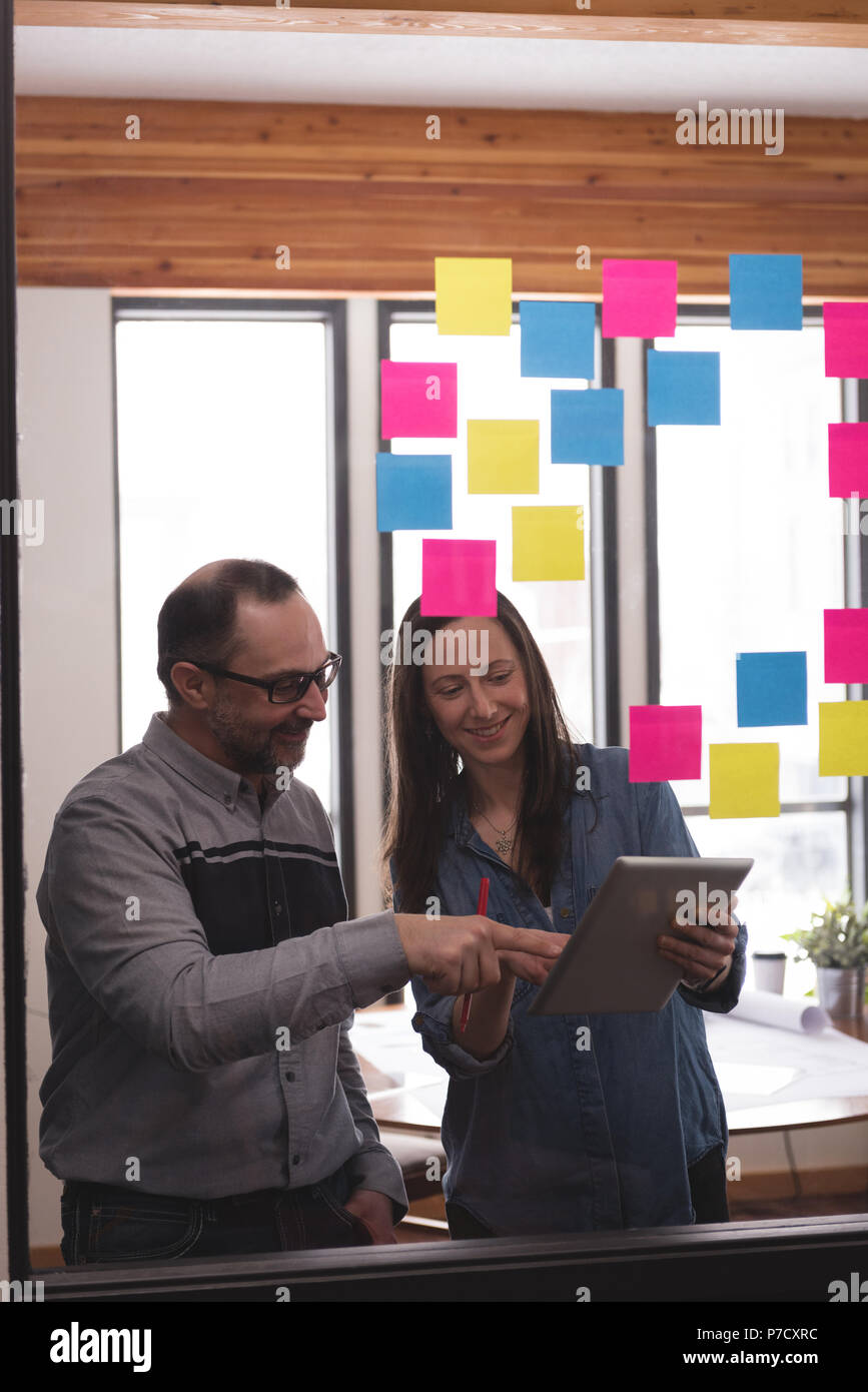 Businesswoman looking over male colleagues shoulder pointing at digital ...