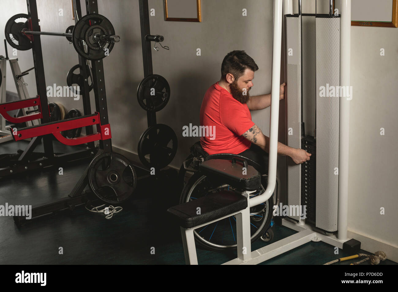 Handicapped man on wheelchair increasing weight of pulldown exercise ...