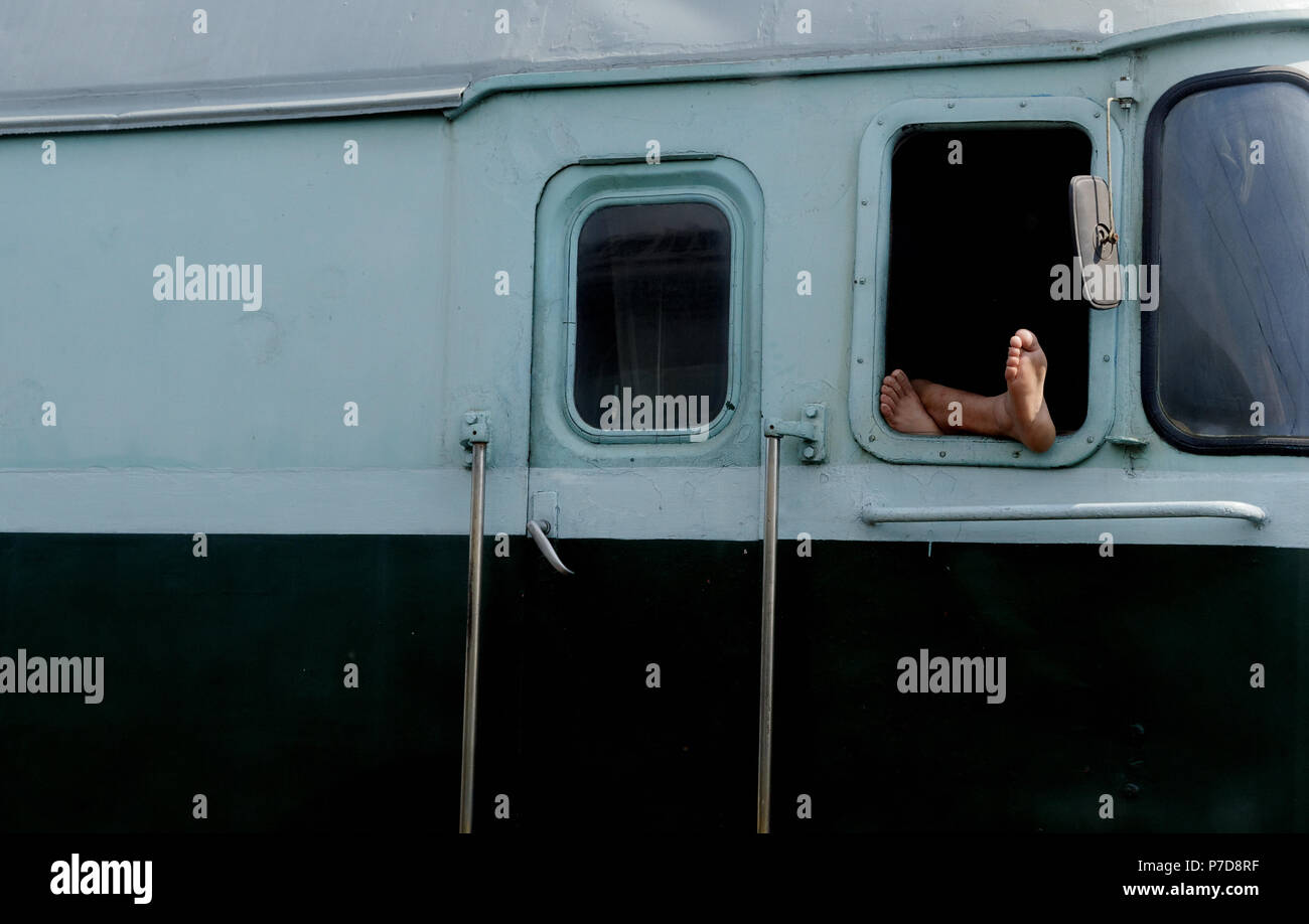North Korean train driver resting with bare feet hanging out of the ...