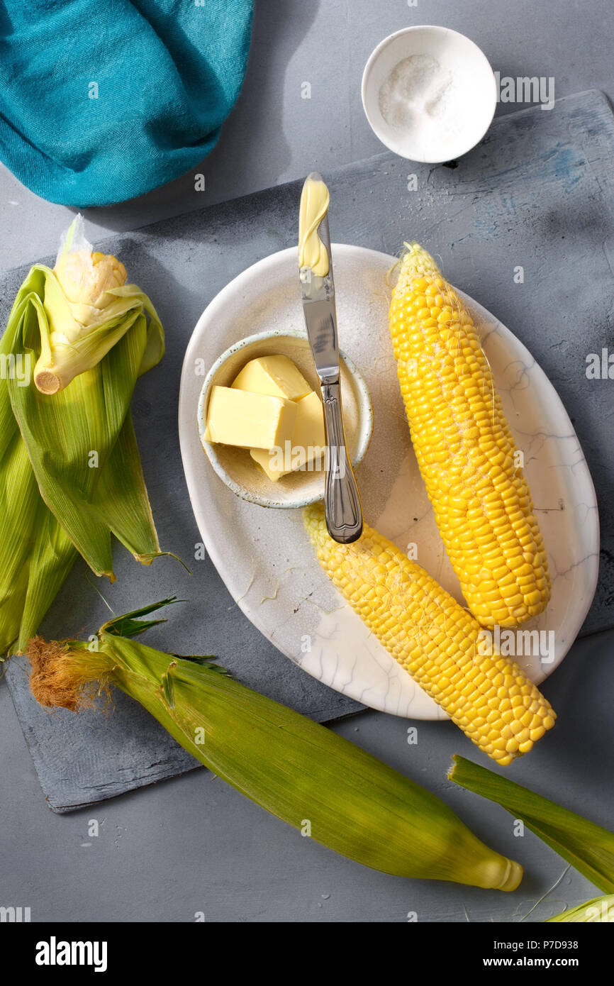 Recipe cooking sweet corn. Raw sweet corn with butter and salt on gray ...