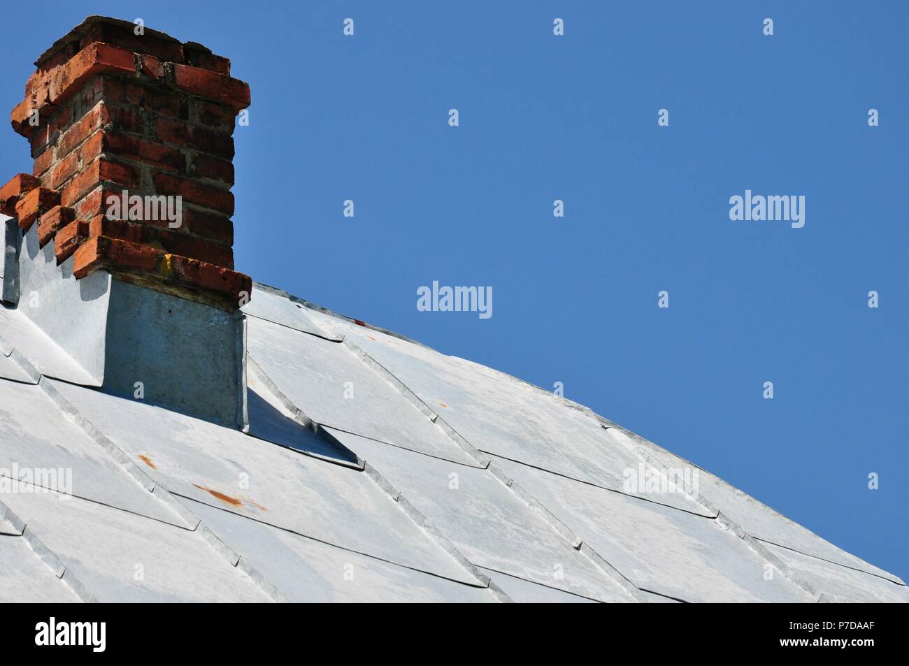 Sheet grey metal roof with a traditional chimney place in the up left ...