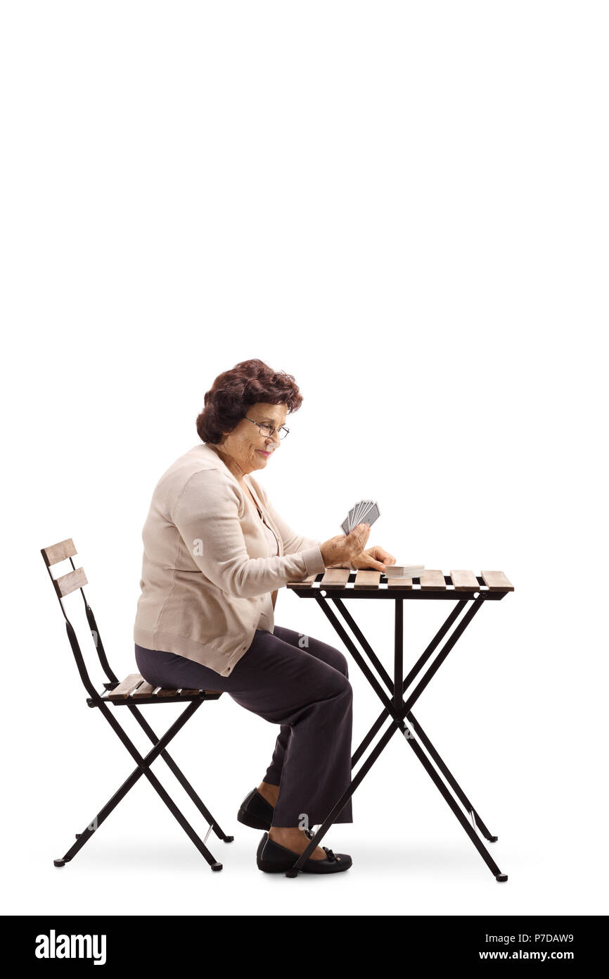 Senior lady sitting at a table and playing cards isolated on white ...