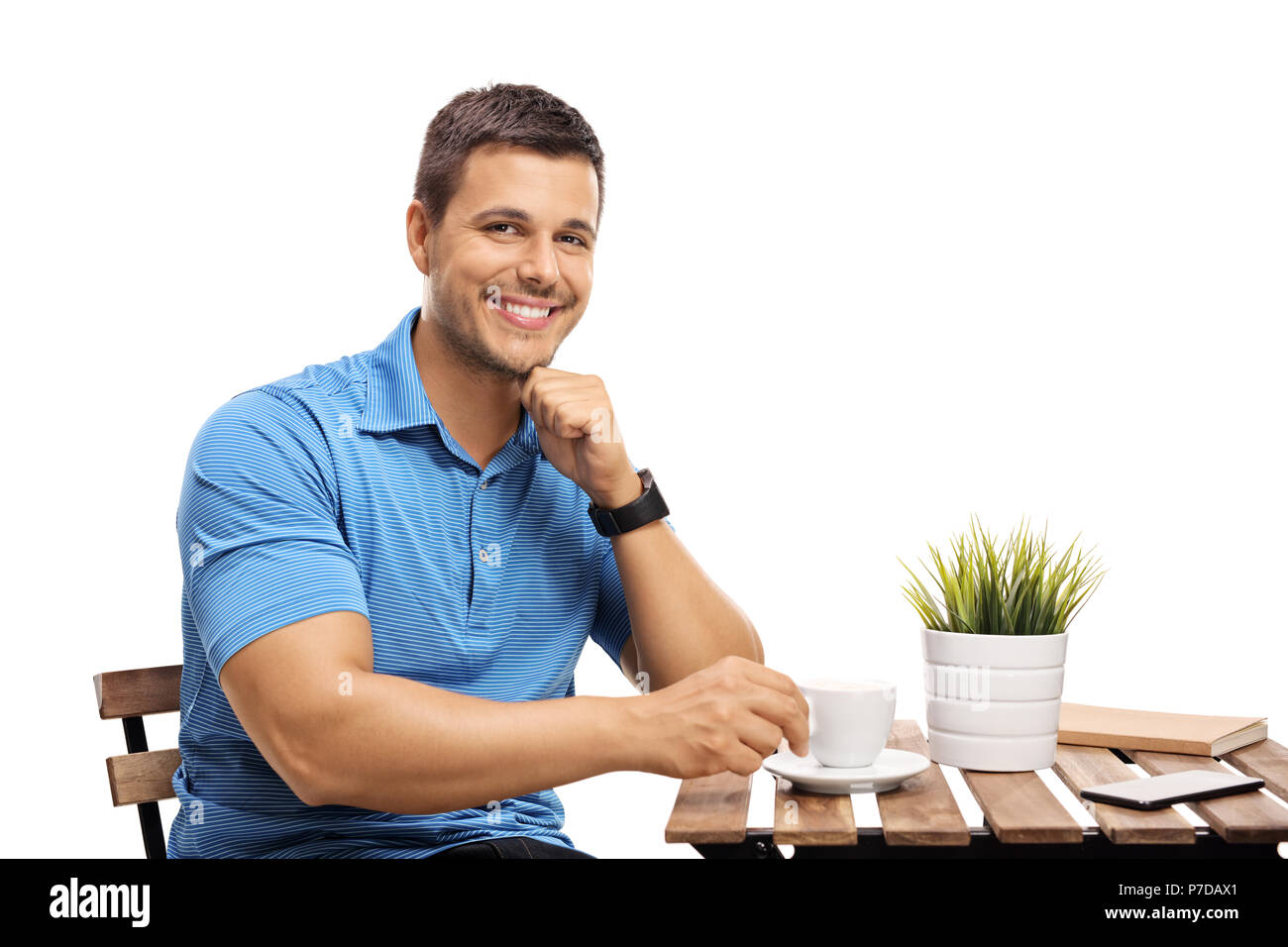 Young man sitting at a coffee table and smiling isolated on white ...
