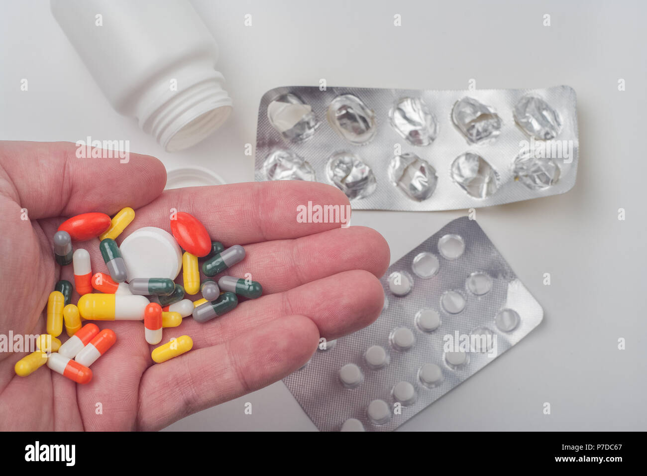 Handful of different pills in mans hand on white background with ...