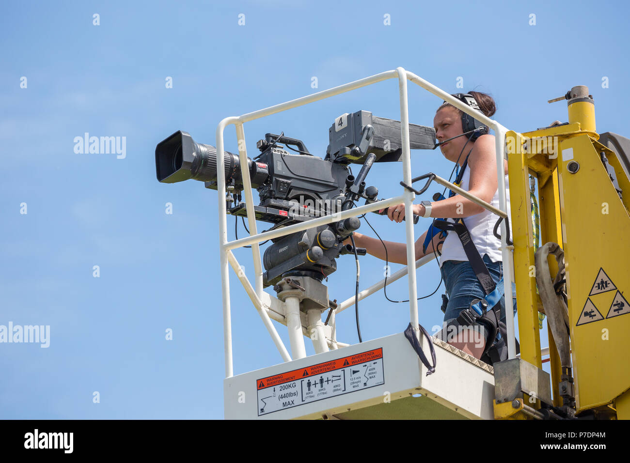 Close up of television camerawoman isolated on elevated platform raised ...
