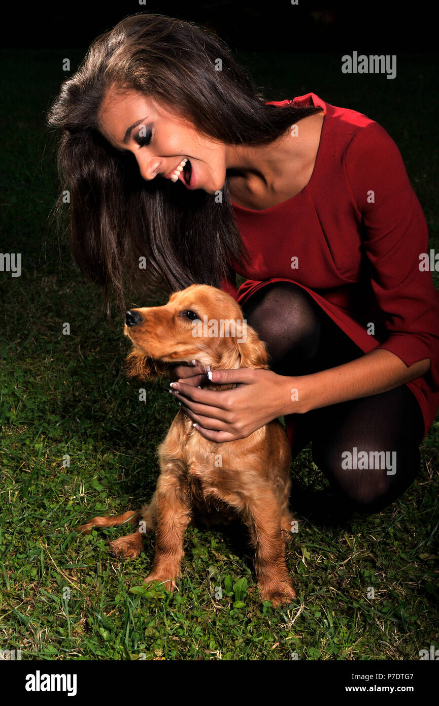 young girl dressed in red plays happy with her dog English Cocker ...