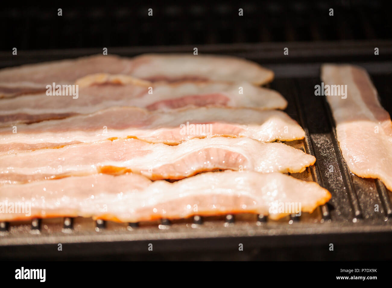 Grilling bacon strips on cast iron griddle in outdoor gas grill Stock ...