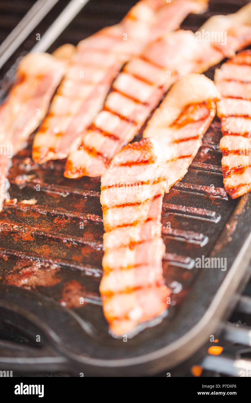 Grilling bacon strips on cast iron griddle in outdoor gas grill Stock ...
