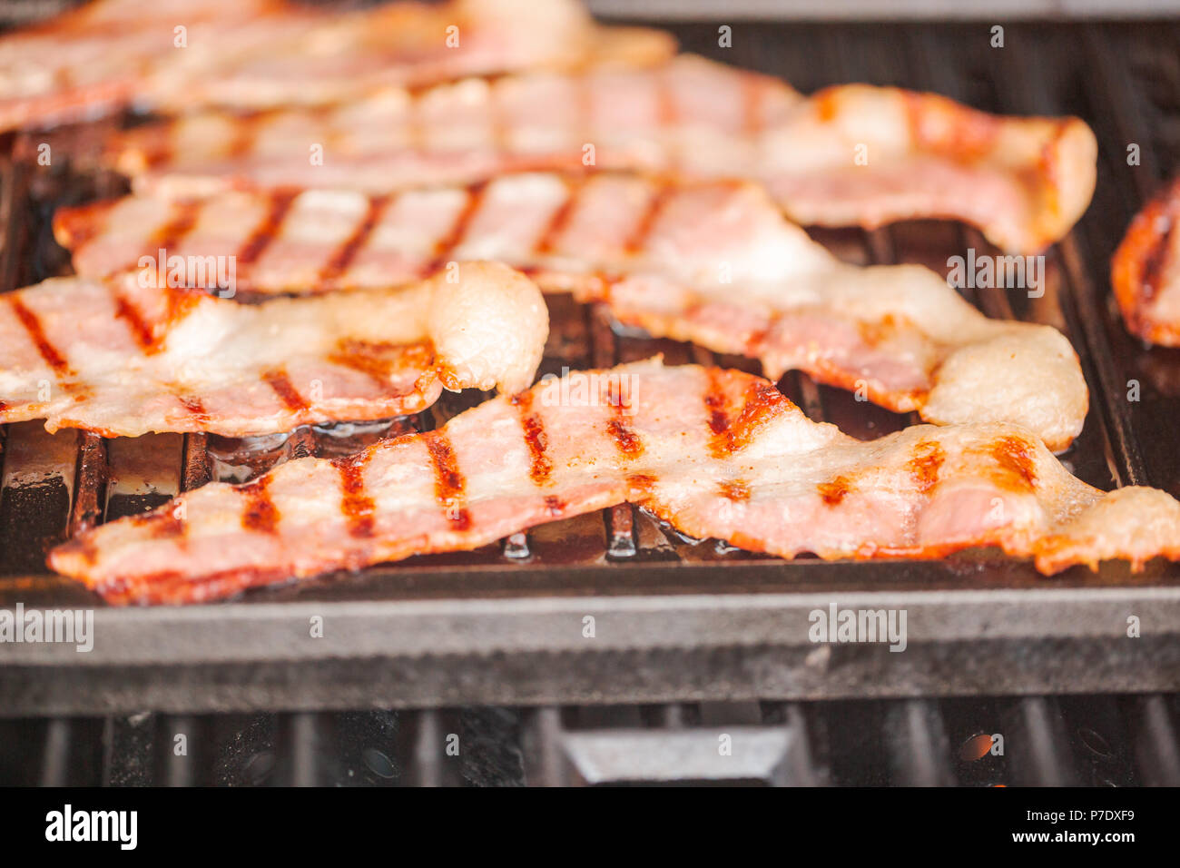 Grilling bacon strips on cast iron griddle in outdoor gas grill Stock ...