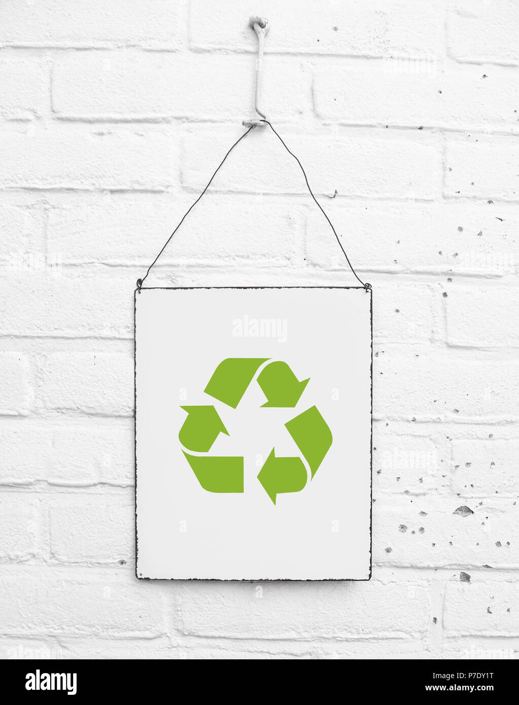 White square metal plate on white brick background with green Recycle ...