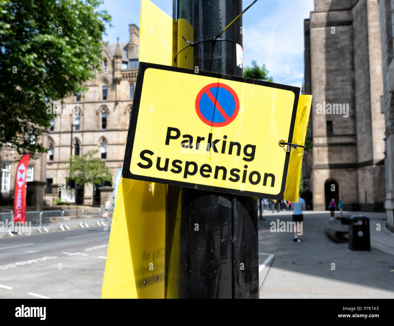 A yellow Parking Suspension sign fixed to a pole in the centre of ...