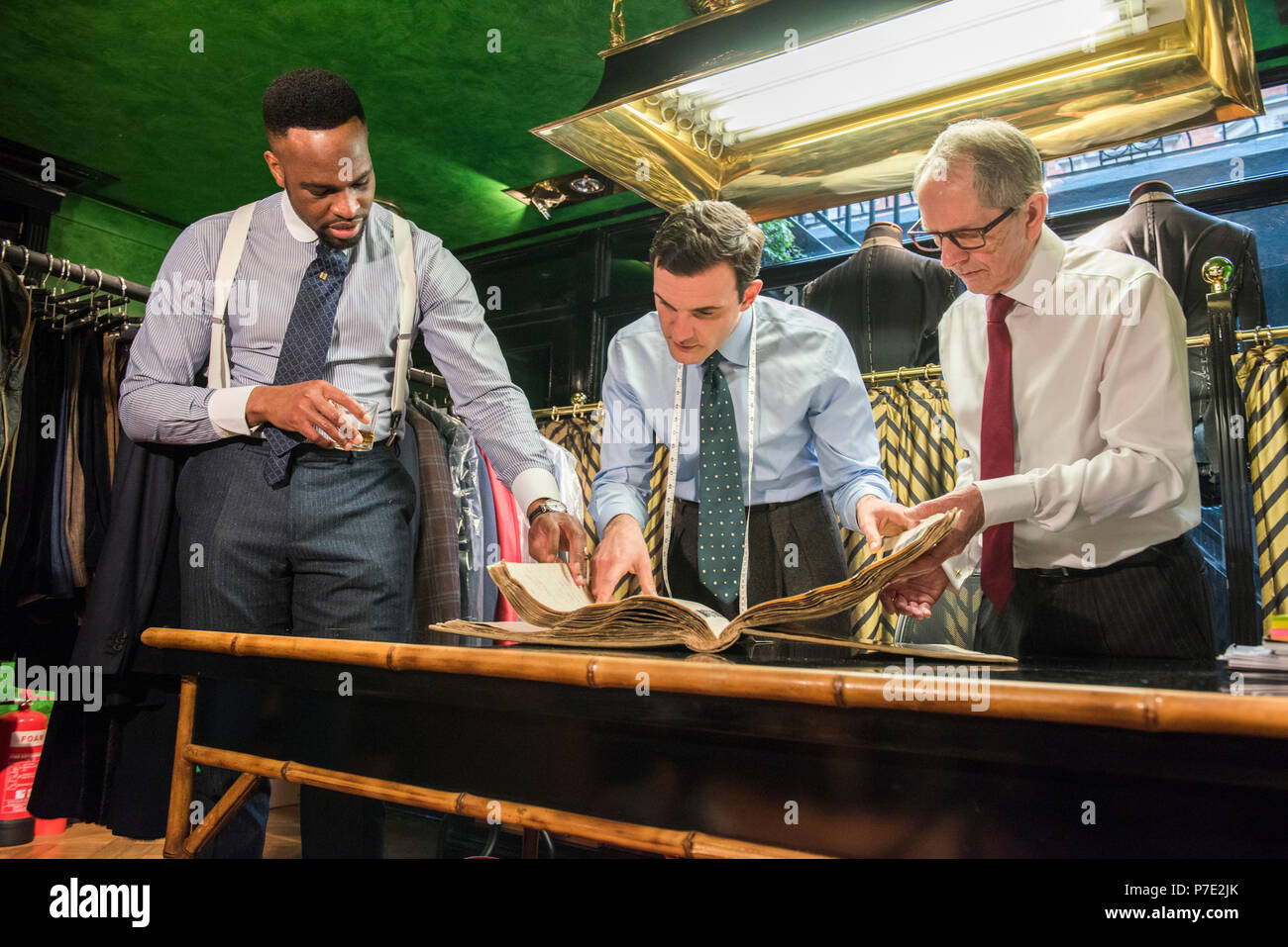 Tailors and customer looking at handmade swatch book in traditional ...