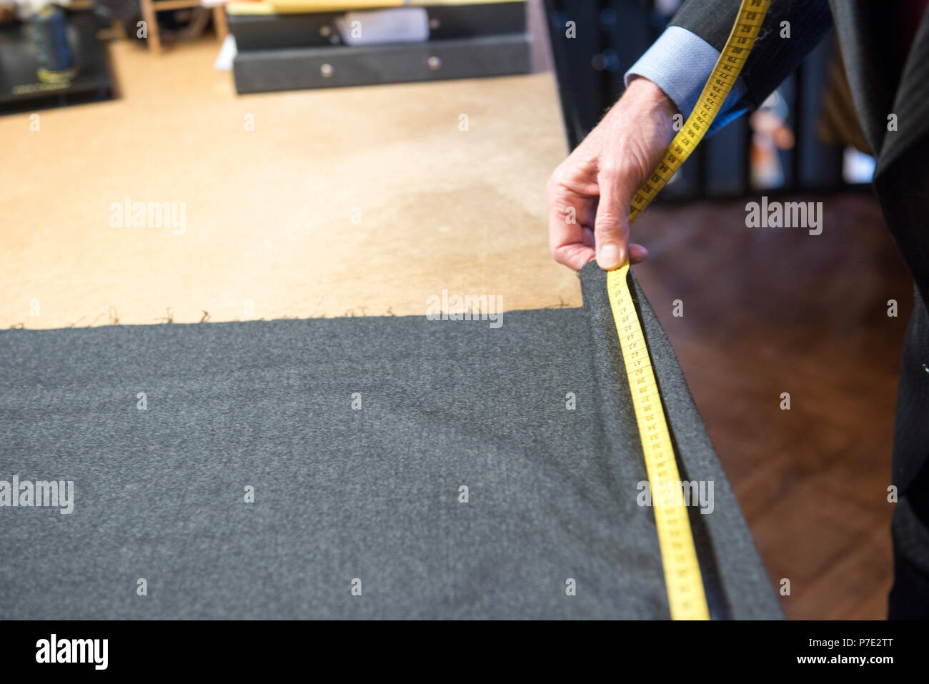 Tailor measuring cloth in tailor shop, detail of hand Stock Photo - Alamy
