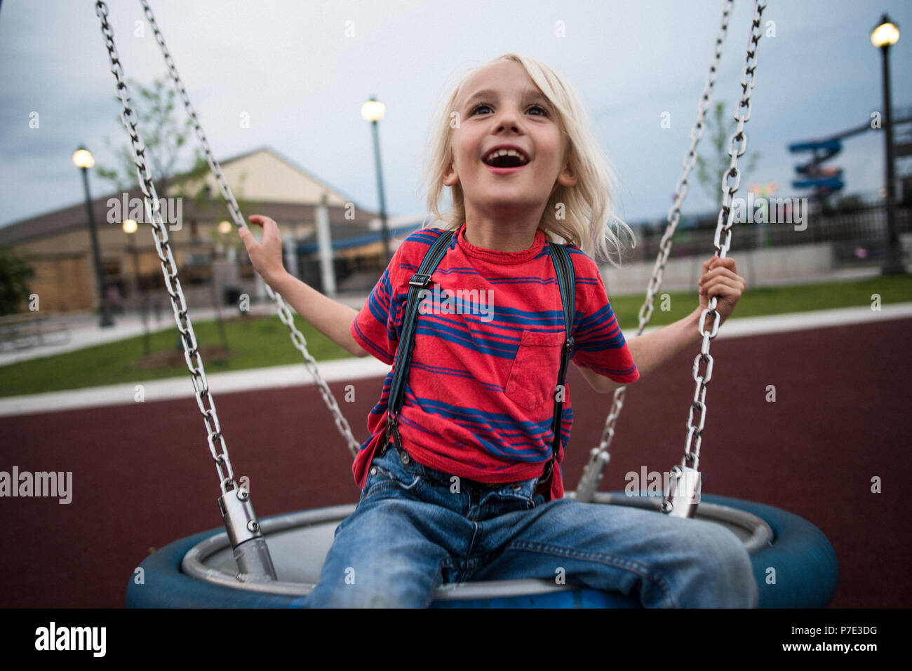 Boy playing on swing in playground Stock Photo - Alamy