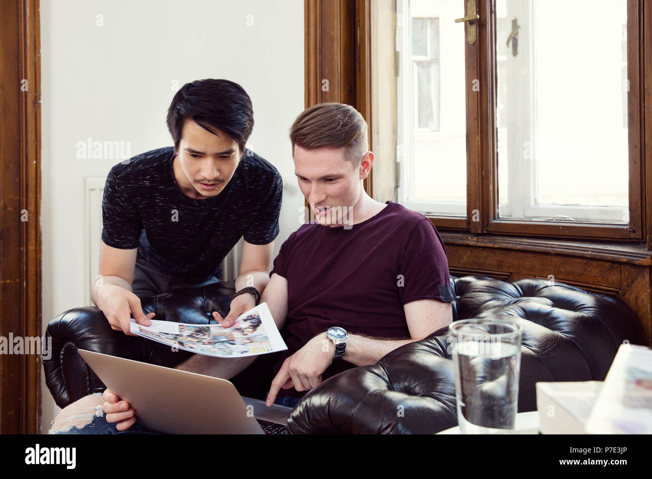 Two young men with print using laptop Stock Photo - Alamy