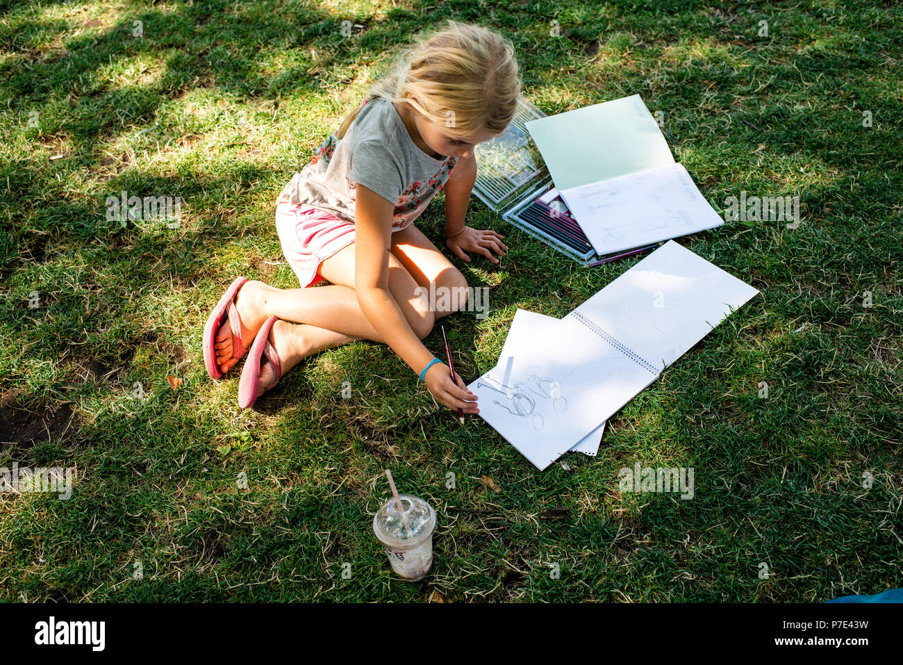 Girl sitting on grass doing homework Stock Photo - Alamy