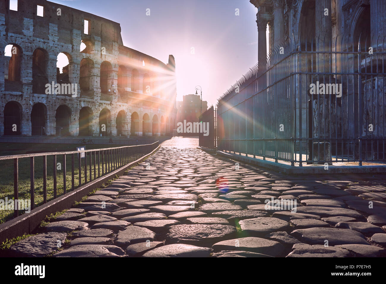 Rome, antique Roman road in cobblestones at dawn, Colosseum and Arch of ...