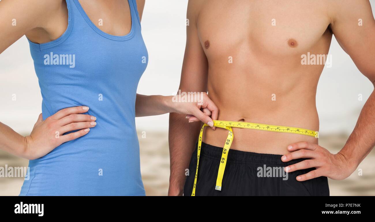 Couple measuring weight with measuring tape on waist on Summer beach ...