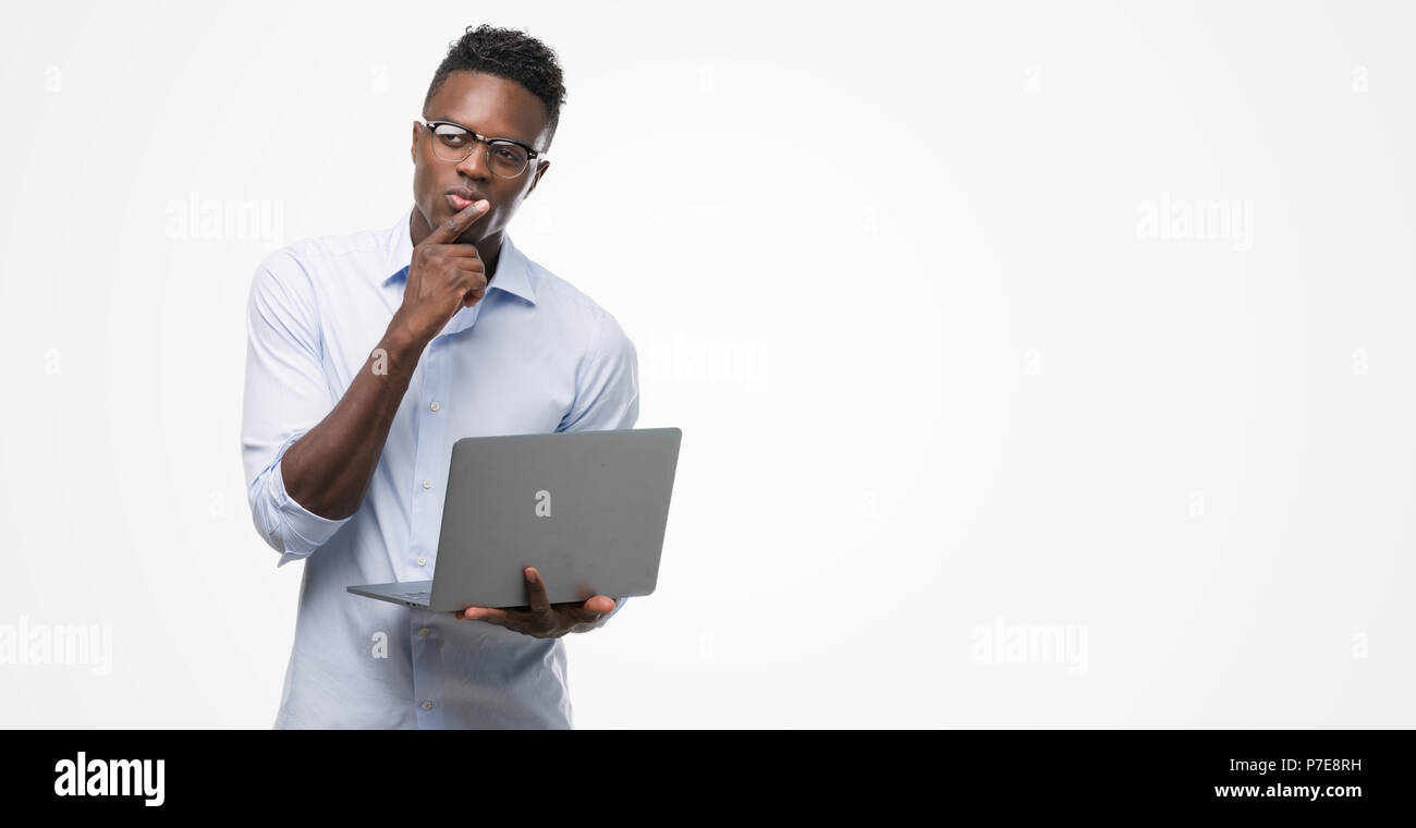 Young african american businessman using computer laptop serious face ...