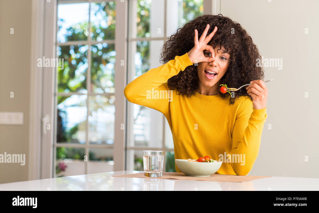 African american woman eating pasta salad with happy face smiling doing ...