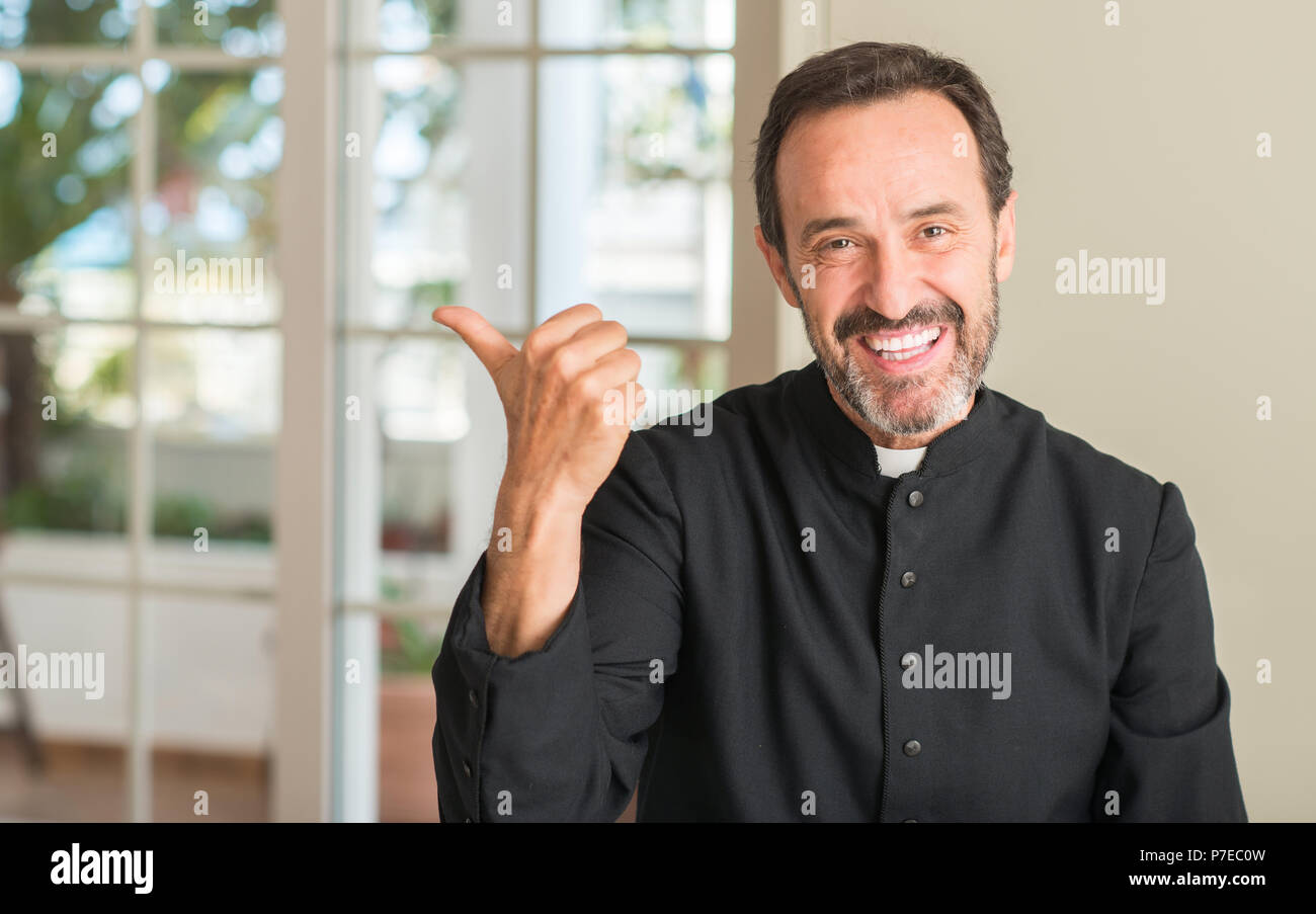Christian priest man pointing with hand and finger up with happy face ...