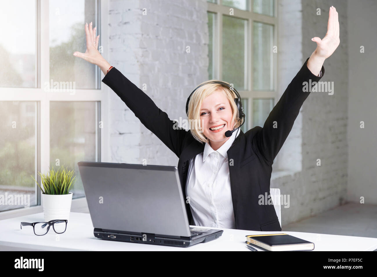 Happy blonde woman, call center operator dressed in black stylish suit ...