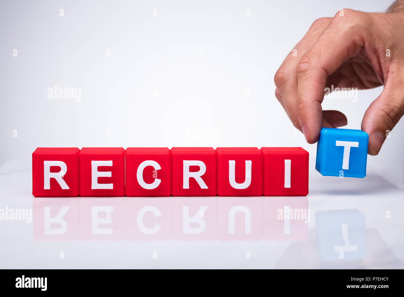 Hand Putting Blue Block Near The Red Blocks To Complete Recruit Word ...