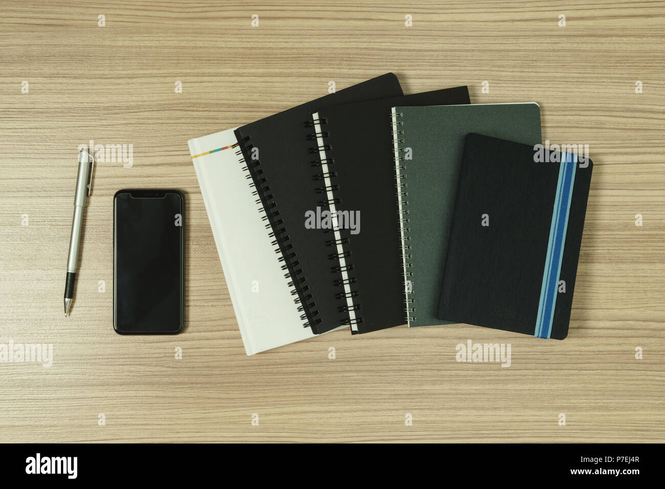 Messy stack of books on wood background with smartphone and pen on wood ...