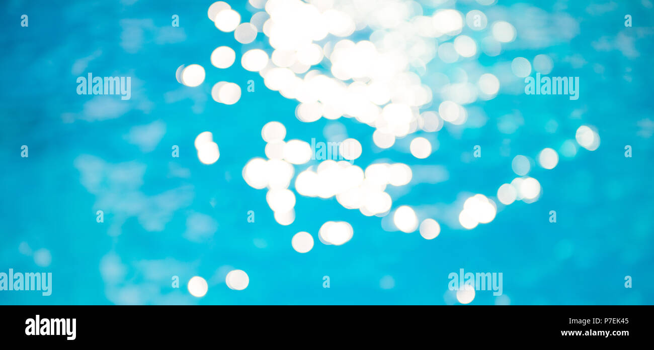 Soft focus bokeh light effects over a rippled, blue water background in ...